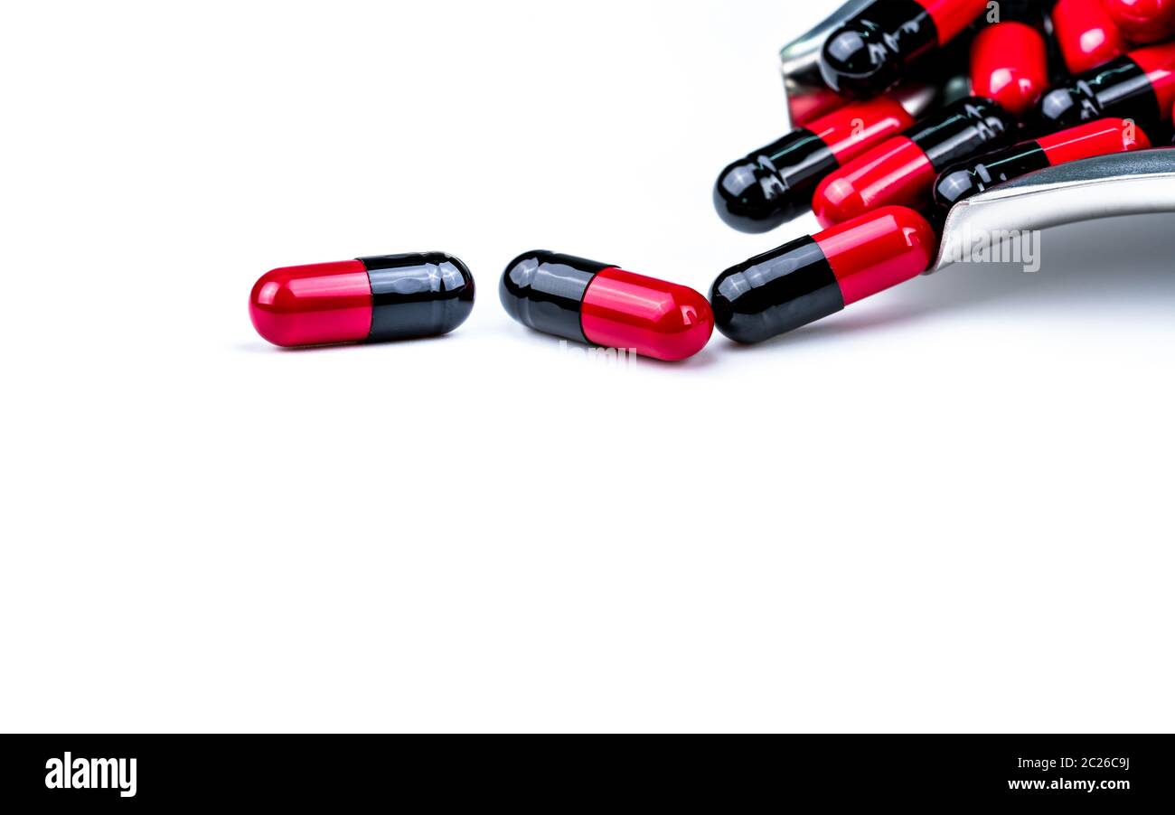 Red and black capsule pills on stainless steel drug tray. Antibiotics ...