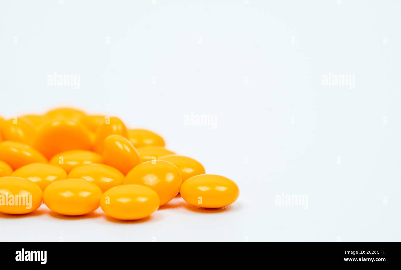 Yellow sugar coated tablets pills on white background with copy space ...
