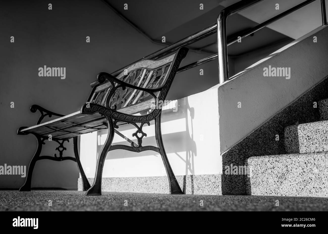 Empty wrought iron bench placed near stairs of the building. Sunshine ...