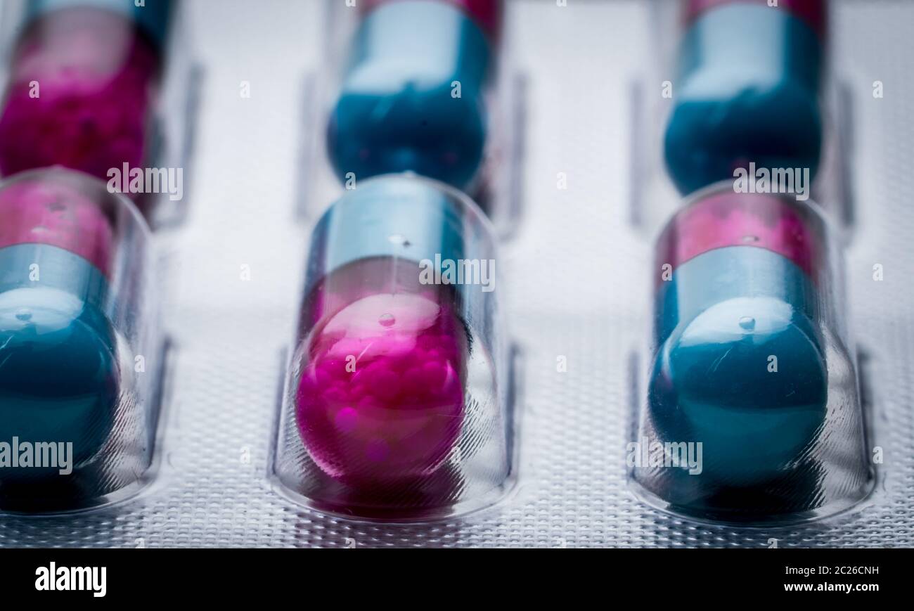 Selective focus of blue, pink capsule with granule in side pills. Pills ...
