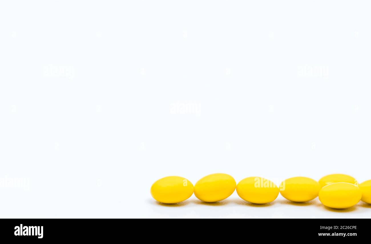 Yellow sugar coated tablets pills on white background with copy space ...