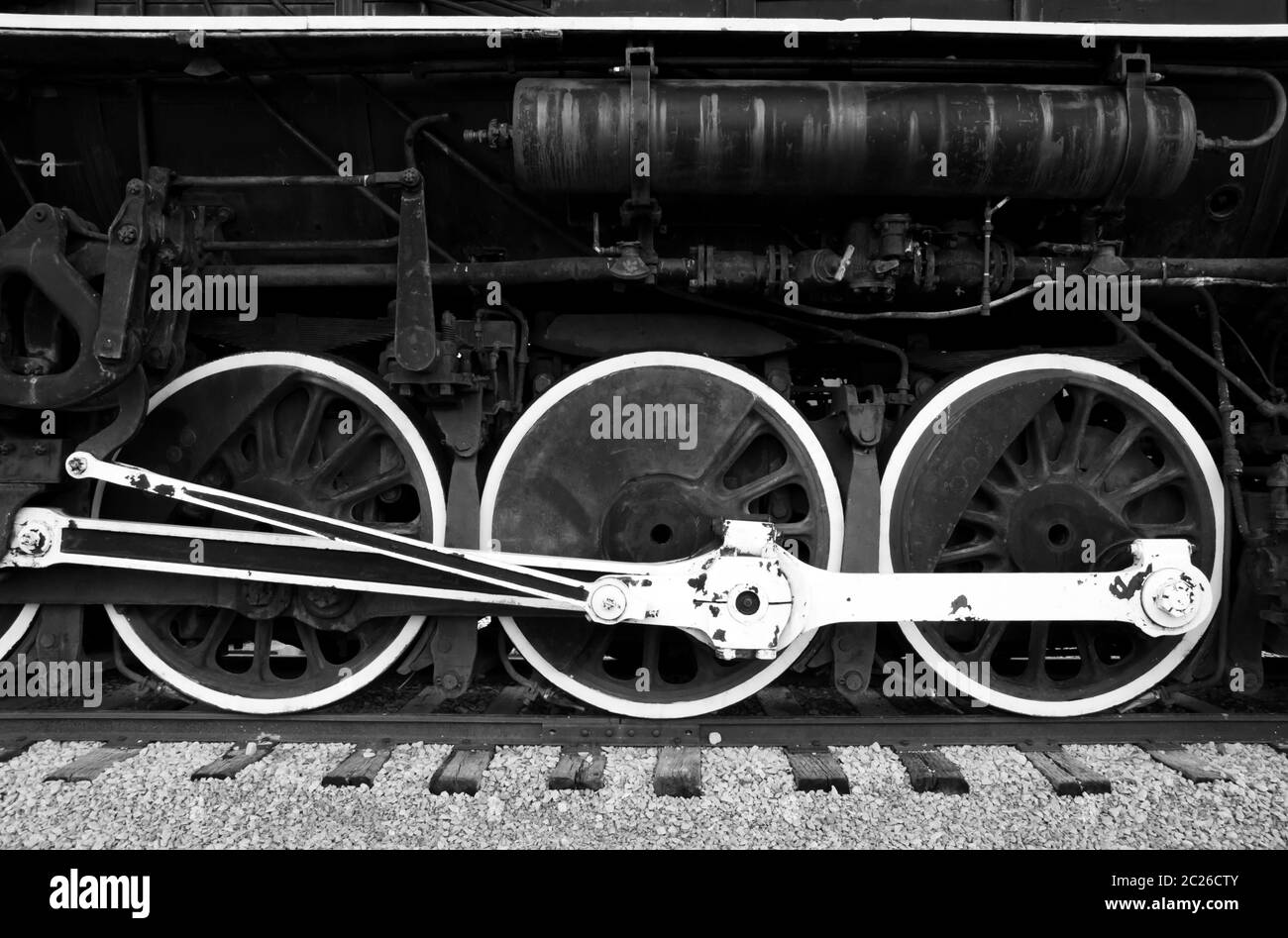The large white rimmed wheels of an old steam engine in black and white ...