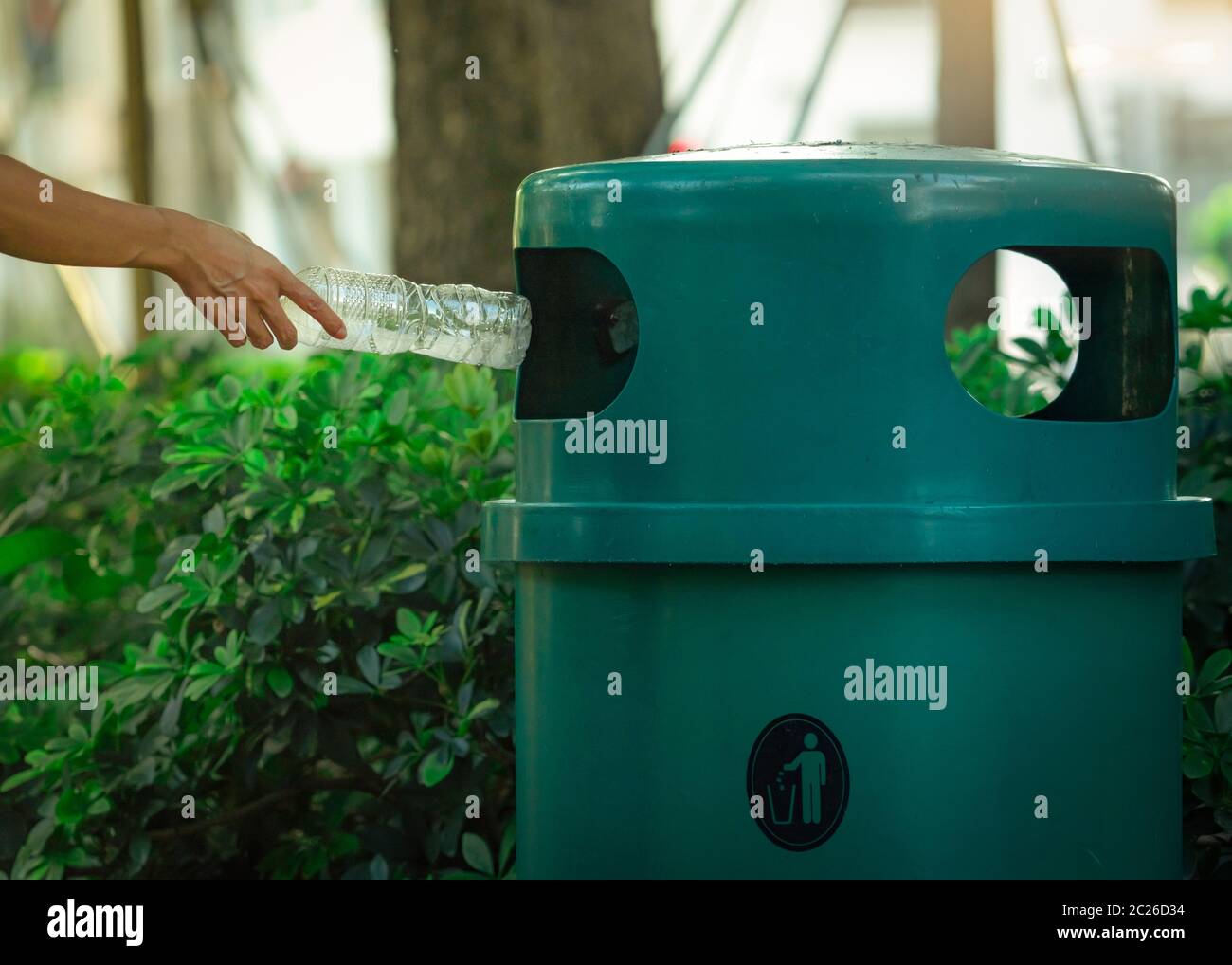People hand throwing empty water bottle in recycle bin at park. Green ...