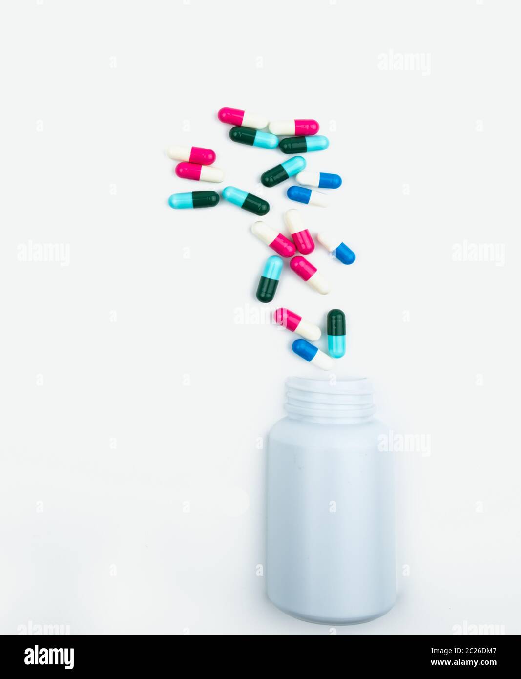 Pouring antibiotics capsule pills into plastic bottle isolated on white ...