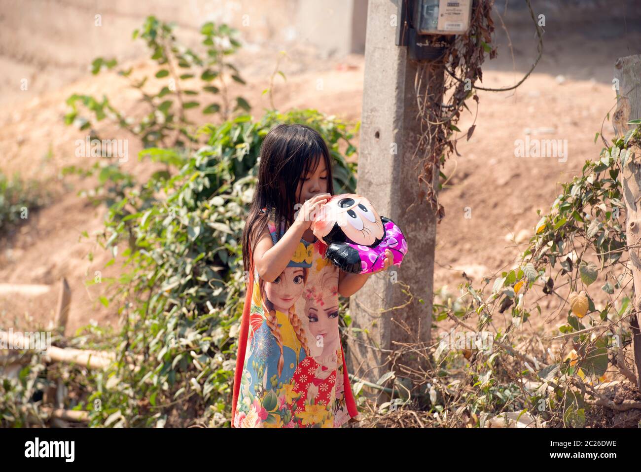 A young, indigenous, ethnic Khmu girl inflating a balloon in her ...