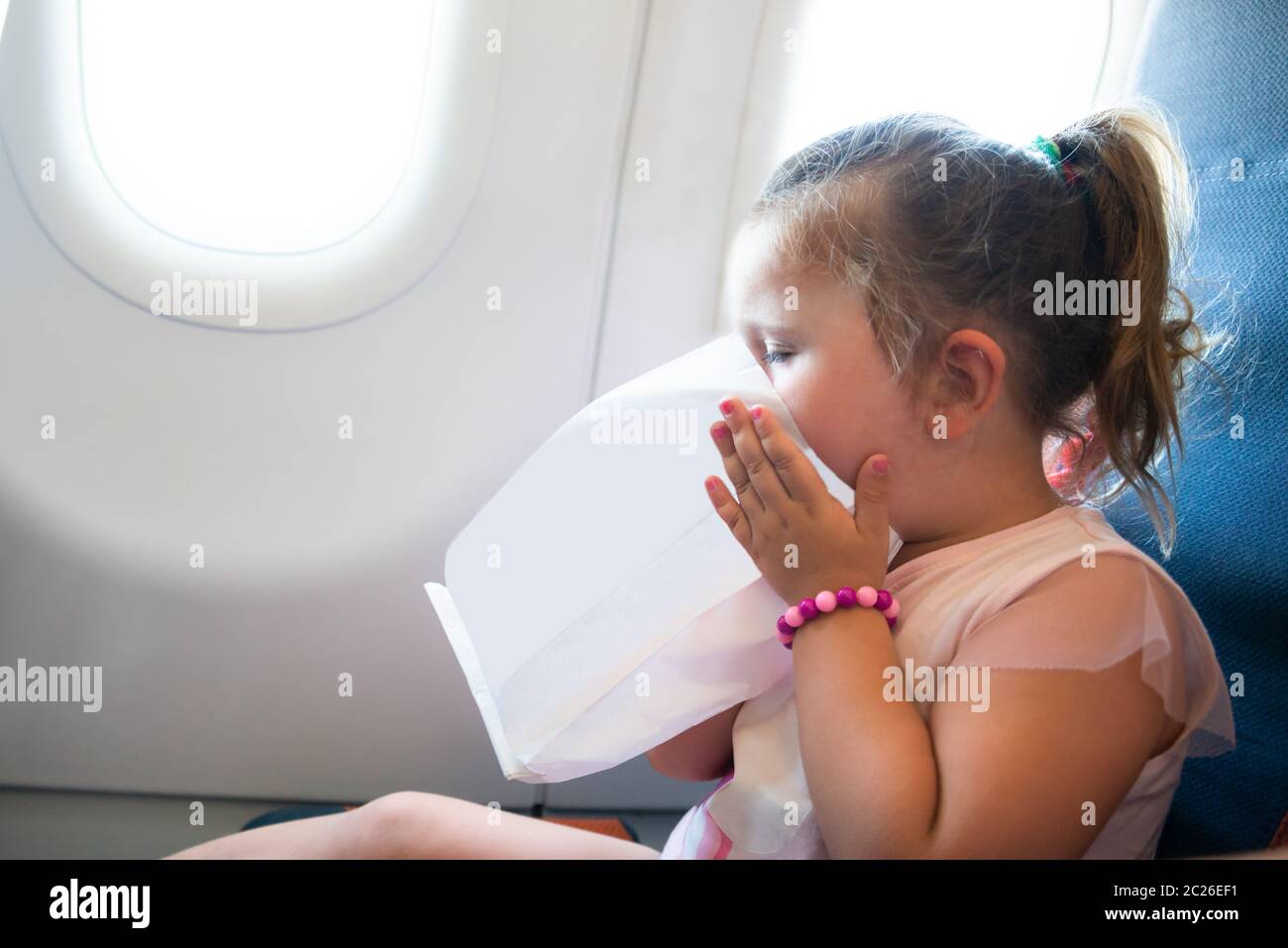 Side View Of Little Girl Is Vomiting In The Airplane Using A Sickness ...