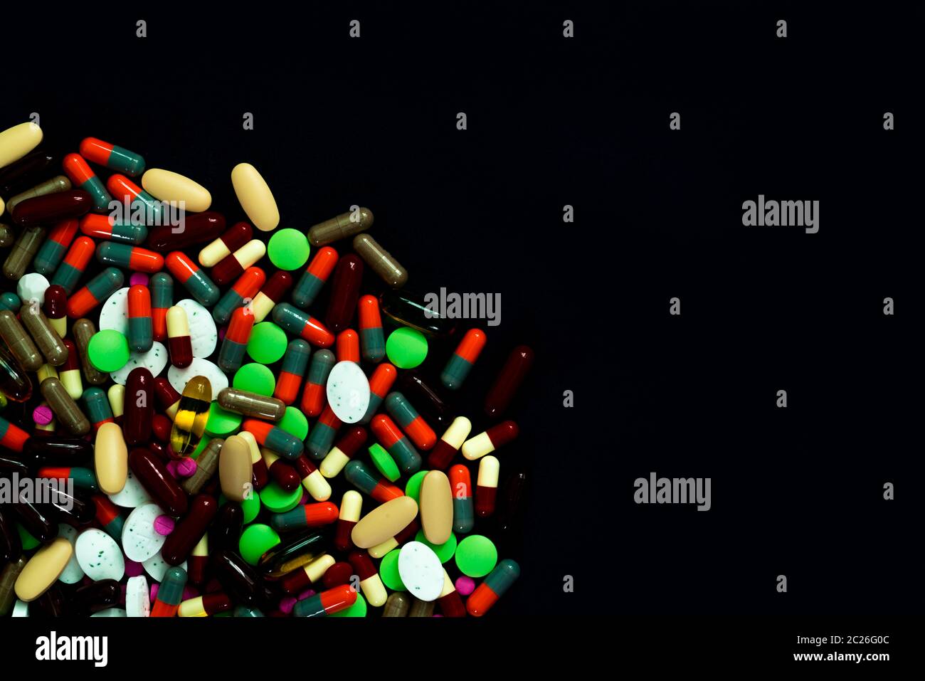 Pile of colorful tablets and capsules pills on black background. Global ...