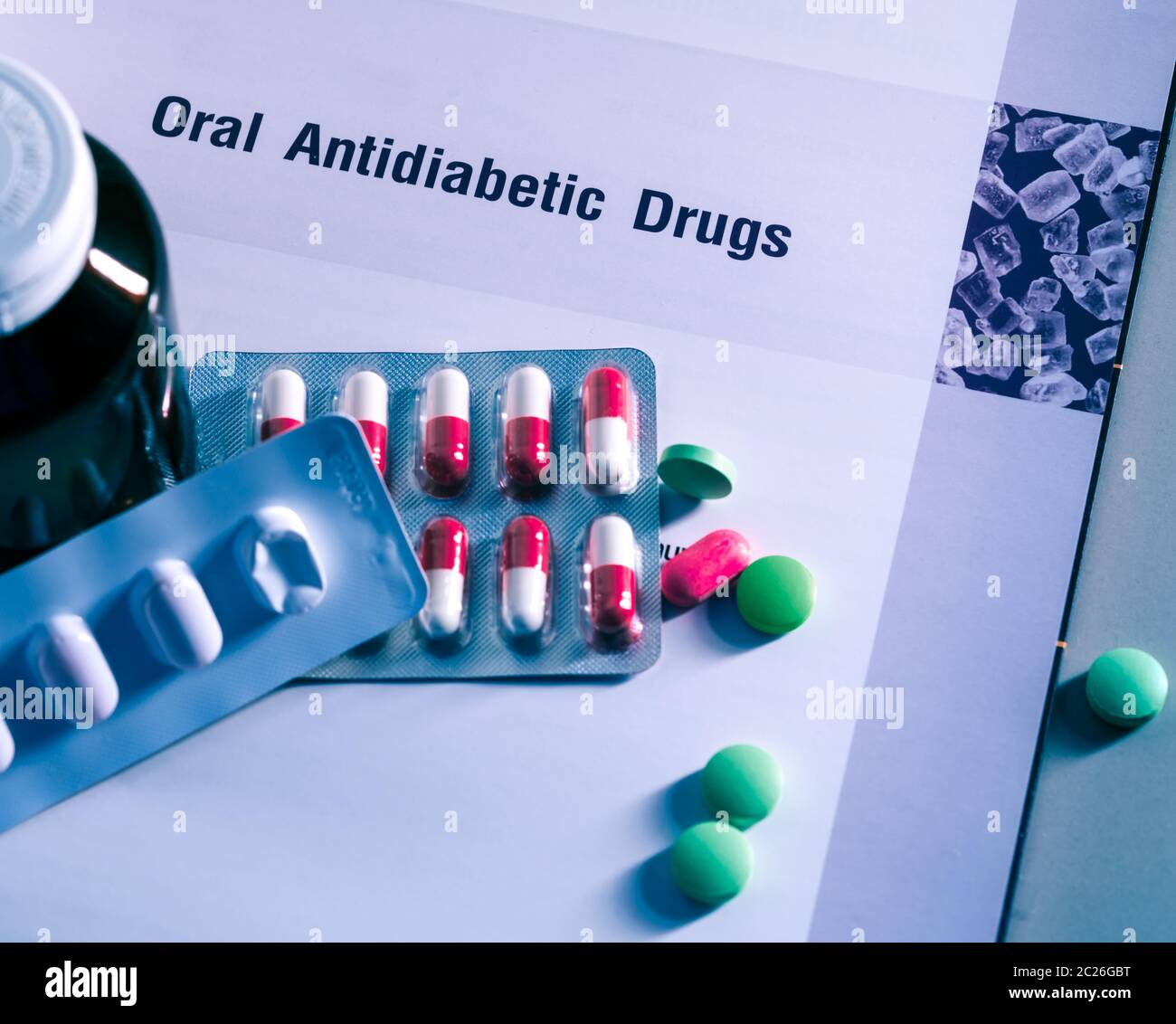 Diabetes drugs in packs and and medicine bottle placed on textbook ...