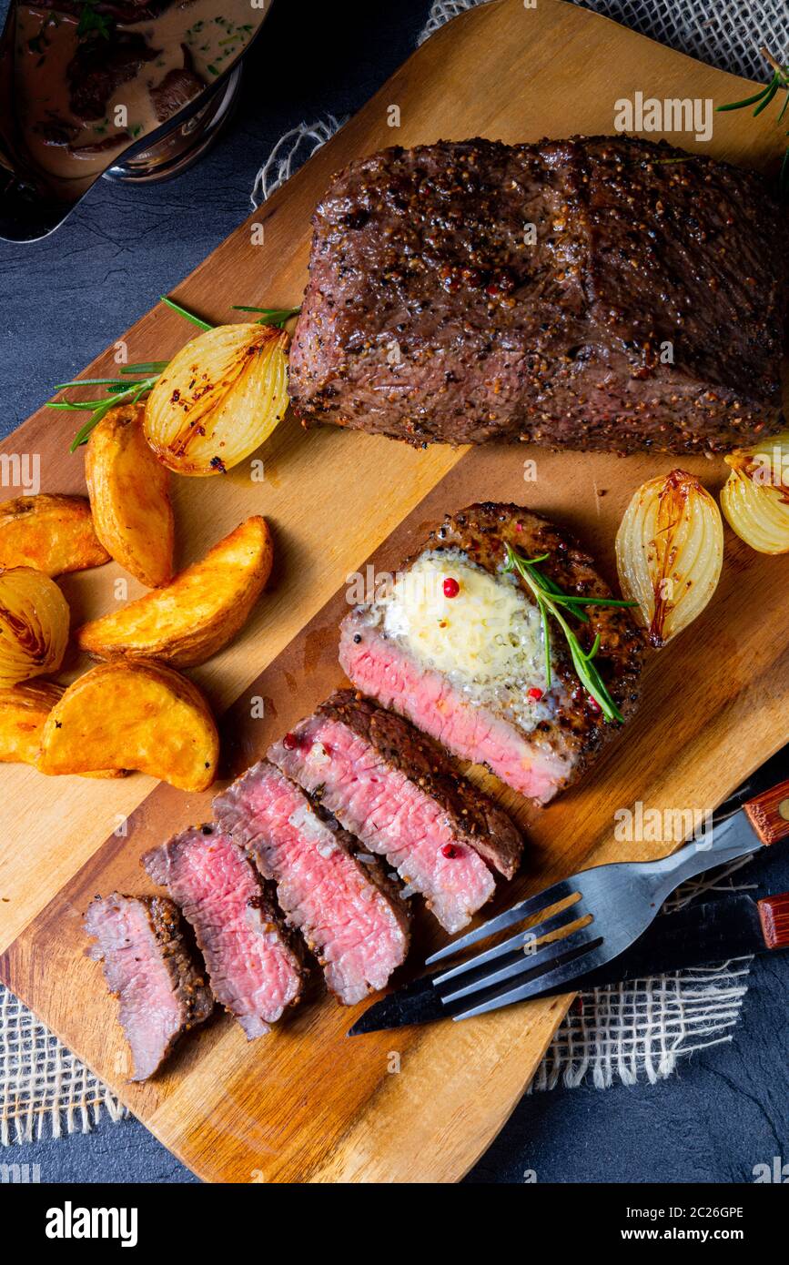rustic medium butter beef steak with herbs and potato wedges Stock ...