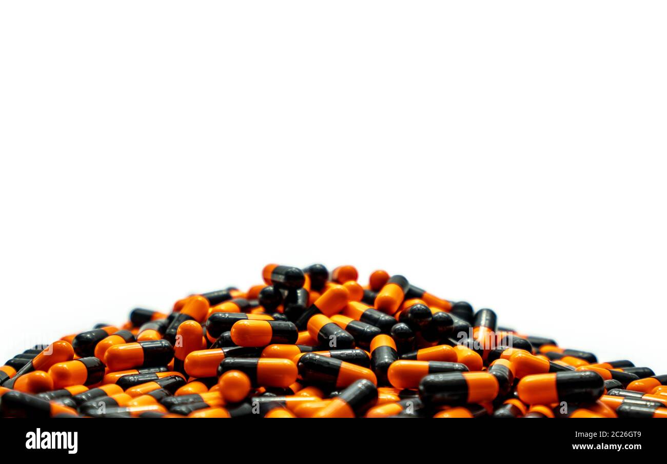 Closeup pile of orange-black capsule pills on white background ...