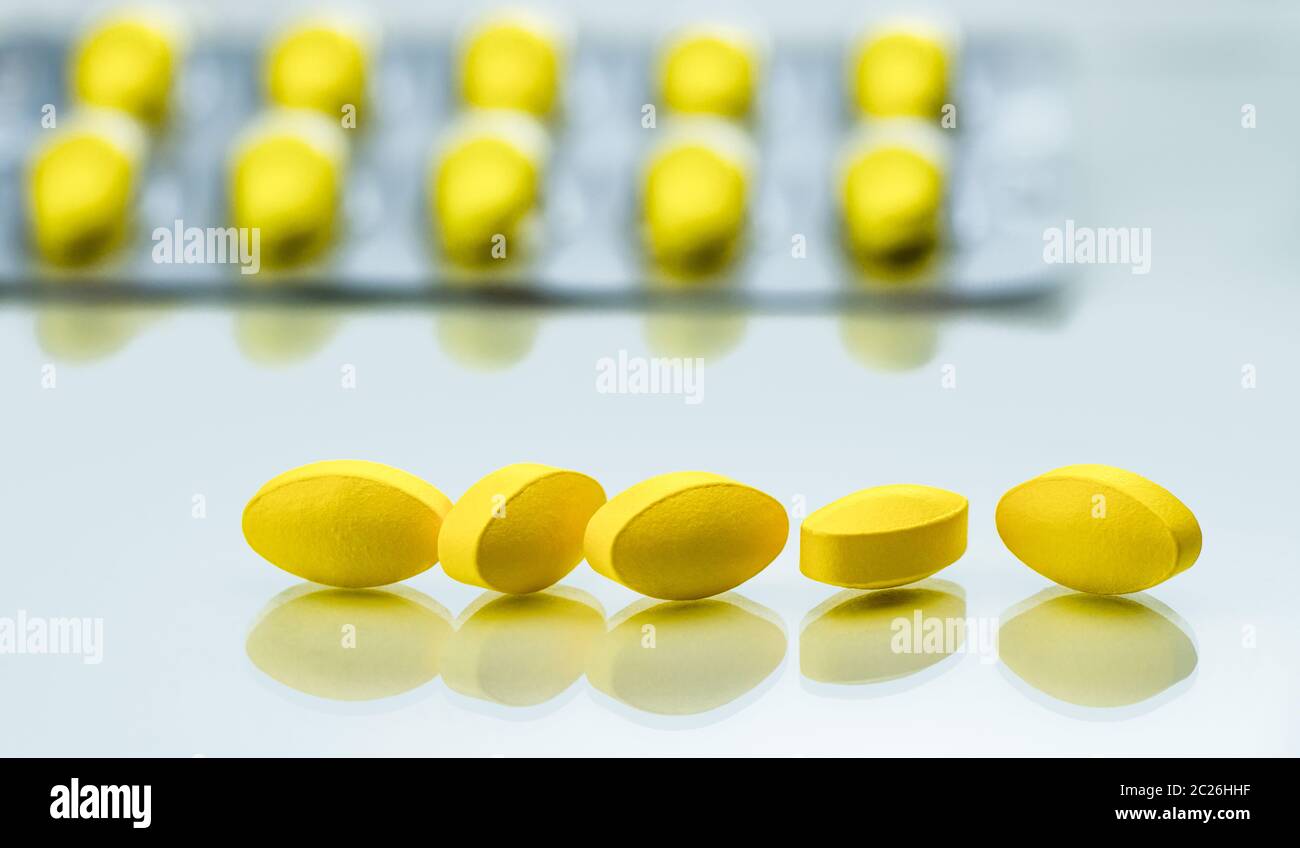 Macro shot detail of yellow oval tablet pills on white background with ...