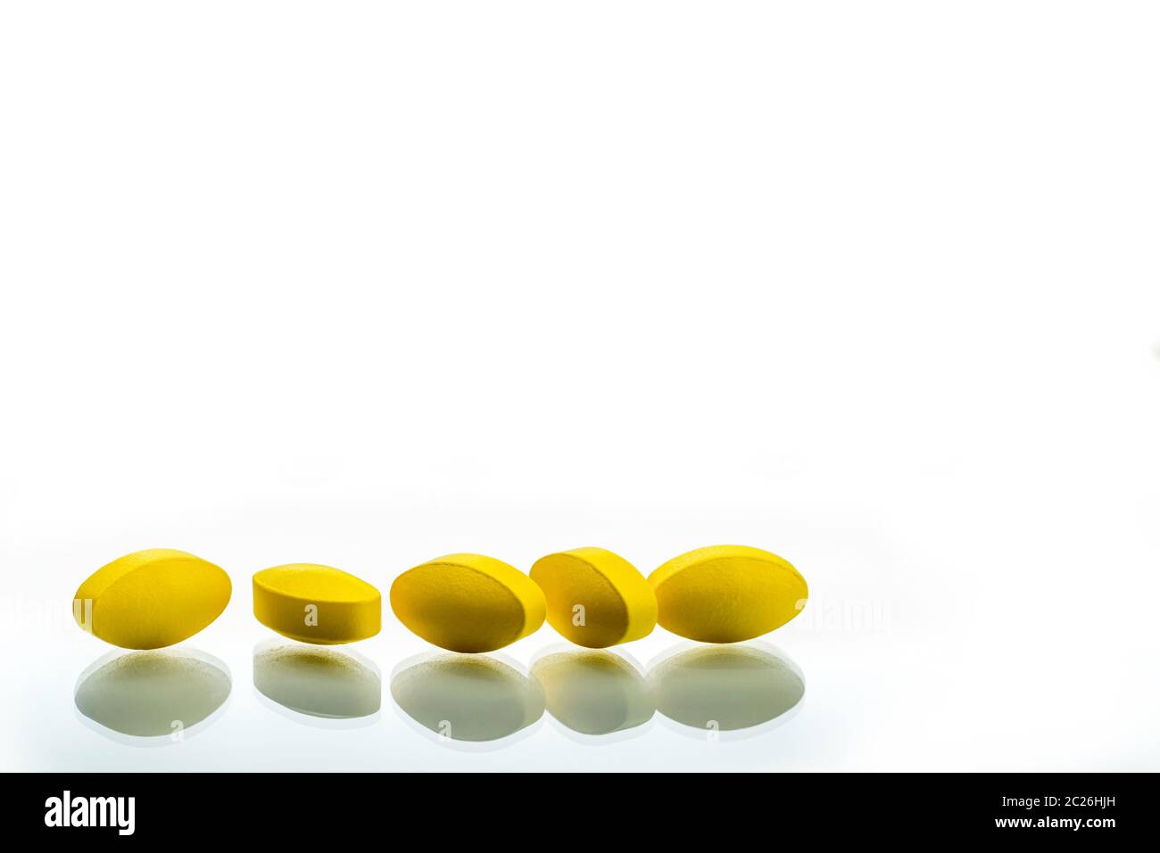 Yellow oval tablet pills with shadows on white background with ...