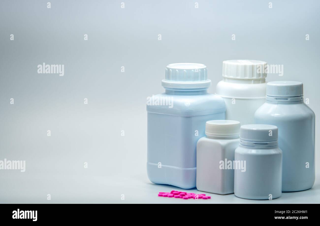 Pink tablet pills with closed blank label bottle on white background ...