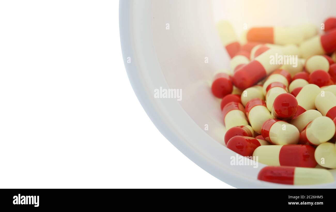 Red and yellow capsules pill in opened white plastic bottle container ...