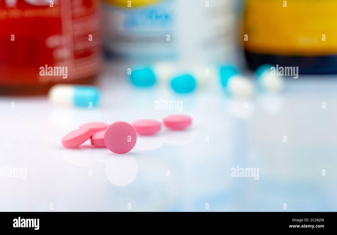 Round pink tablets pill on blurred background of drug bottle ...