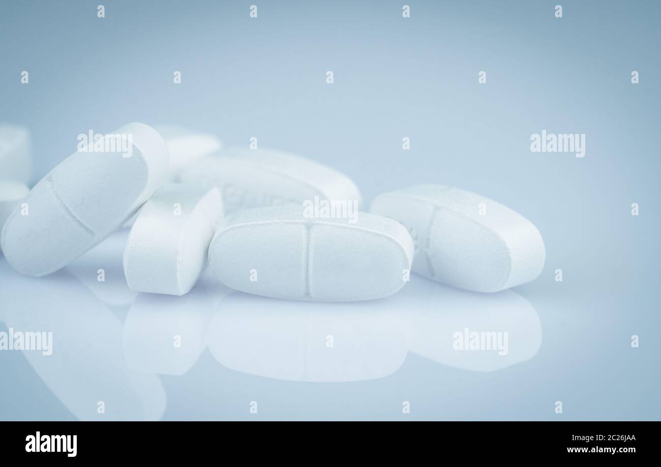 Pile of white oblong tablets pills on gradient background. White ...