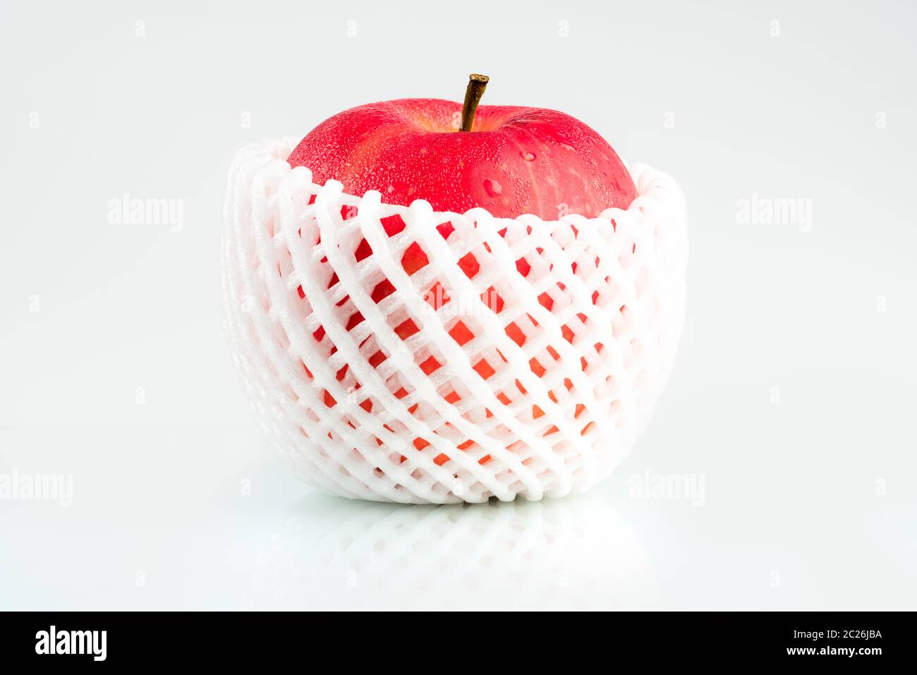 A red apple with water drops on skin in white shockproof foam net wrap ...