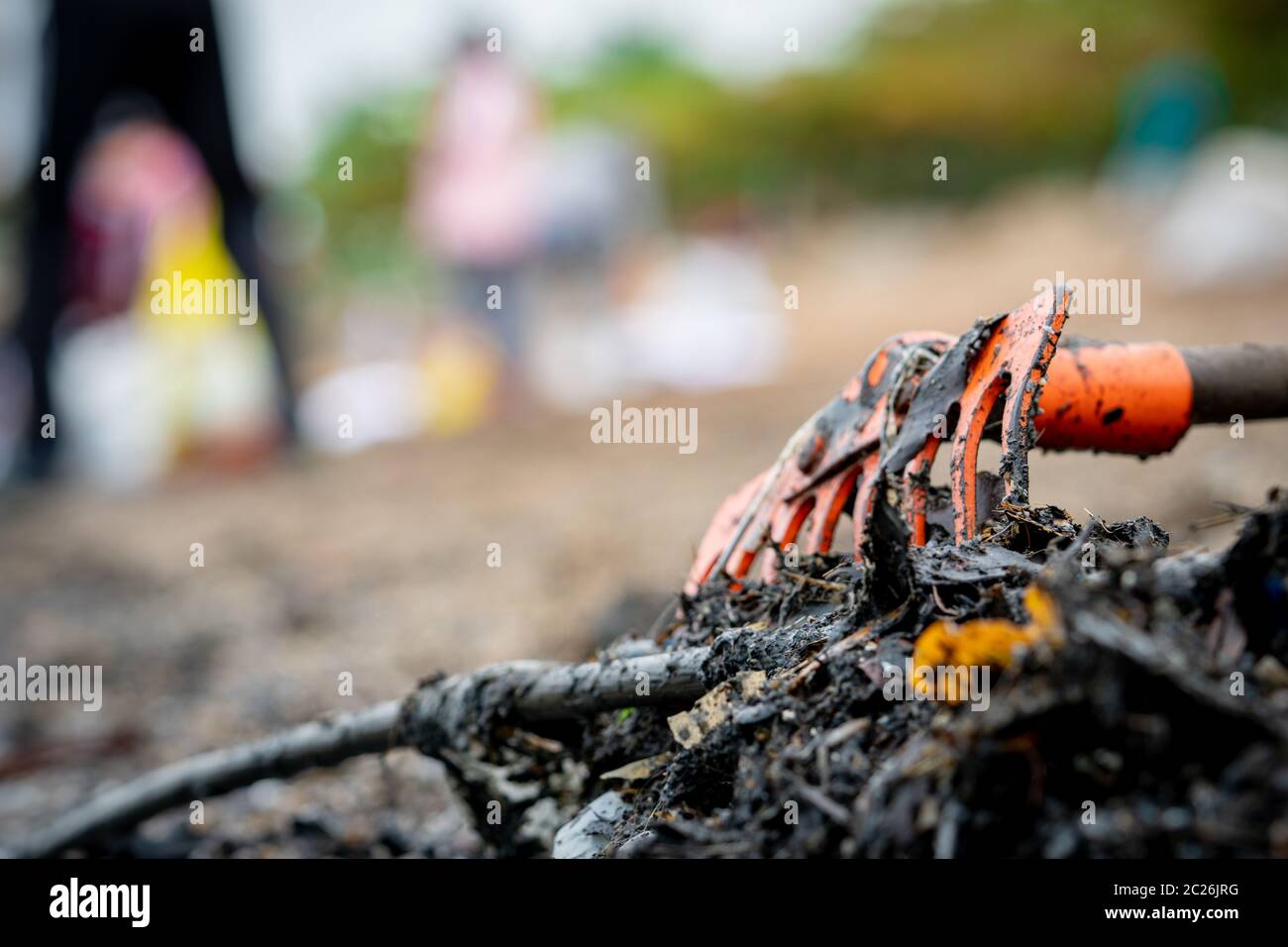 Closeup orange rake on pile of dirty waste on blurred background of ...