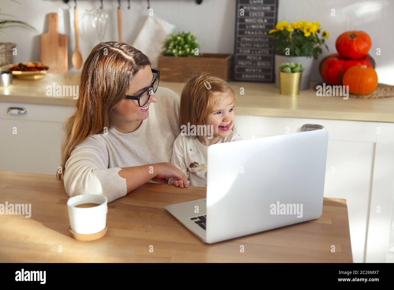 Beautiful mom working at home on a laptop computer while taking care of ...