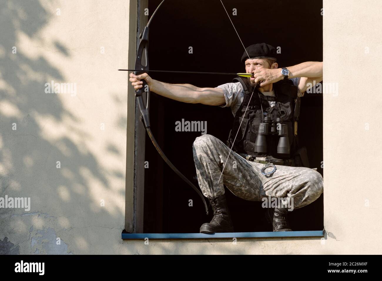 The archer is aiming with bow and arrow in the window, archery concept ...