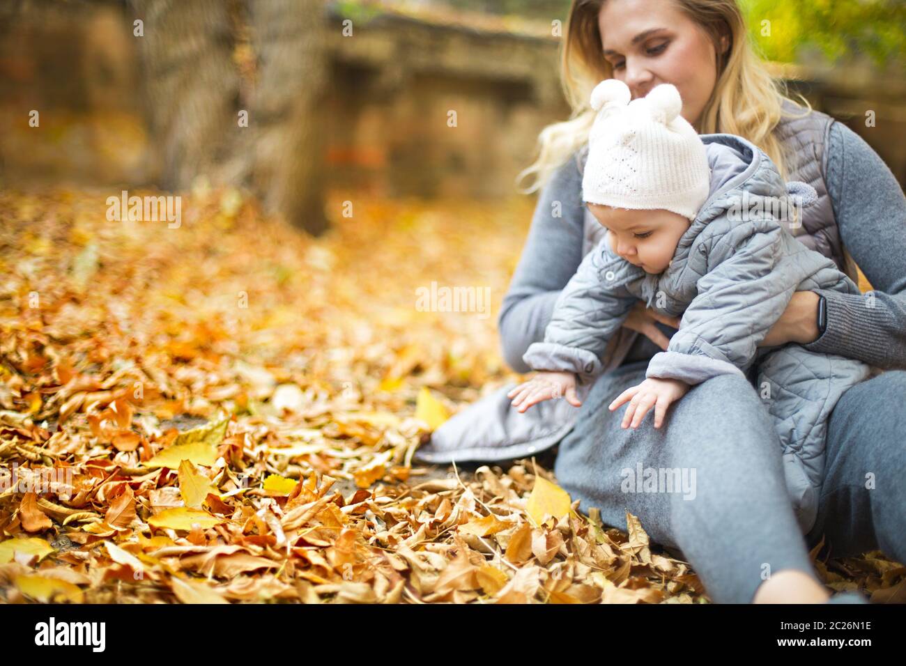 Mother and her little daughter play cuddling on autumn walk in nature ...