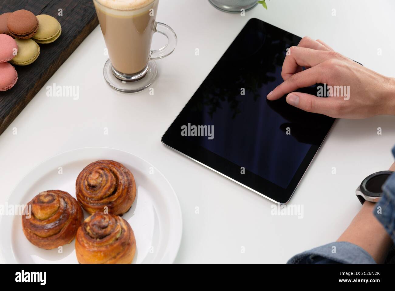 Woman with smartwatch using tablet in coffee shop. Coffee and pastry ...