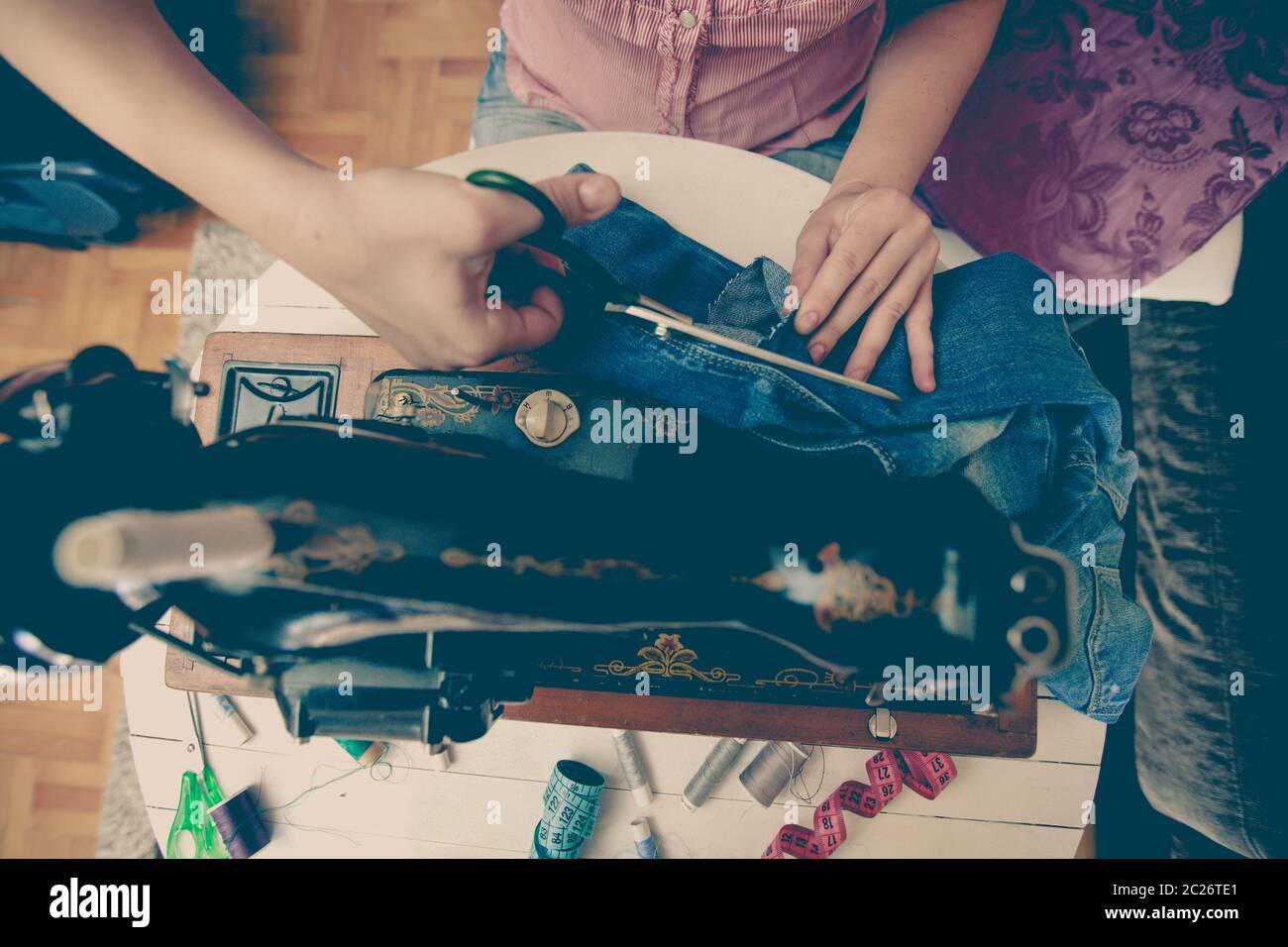 Overhead shot of female hands using scissors cutting blue jeans and ...