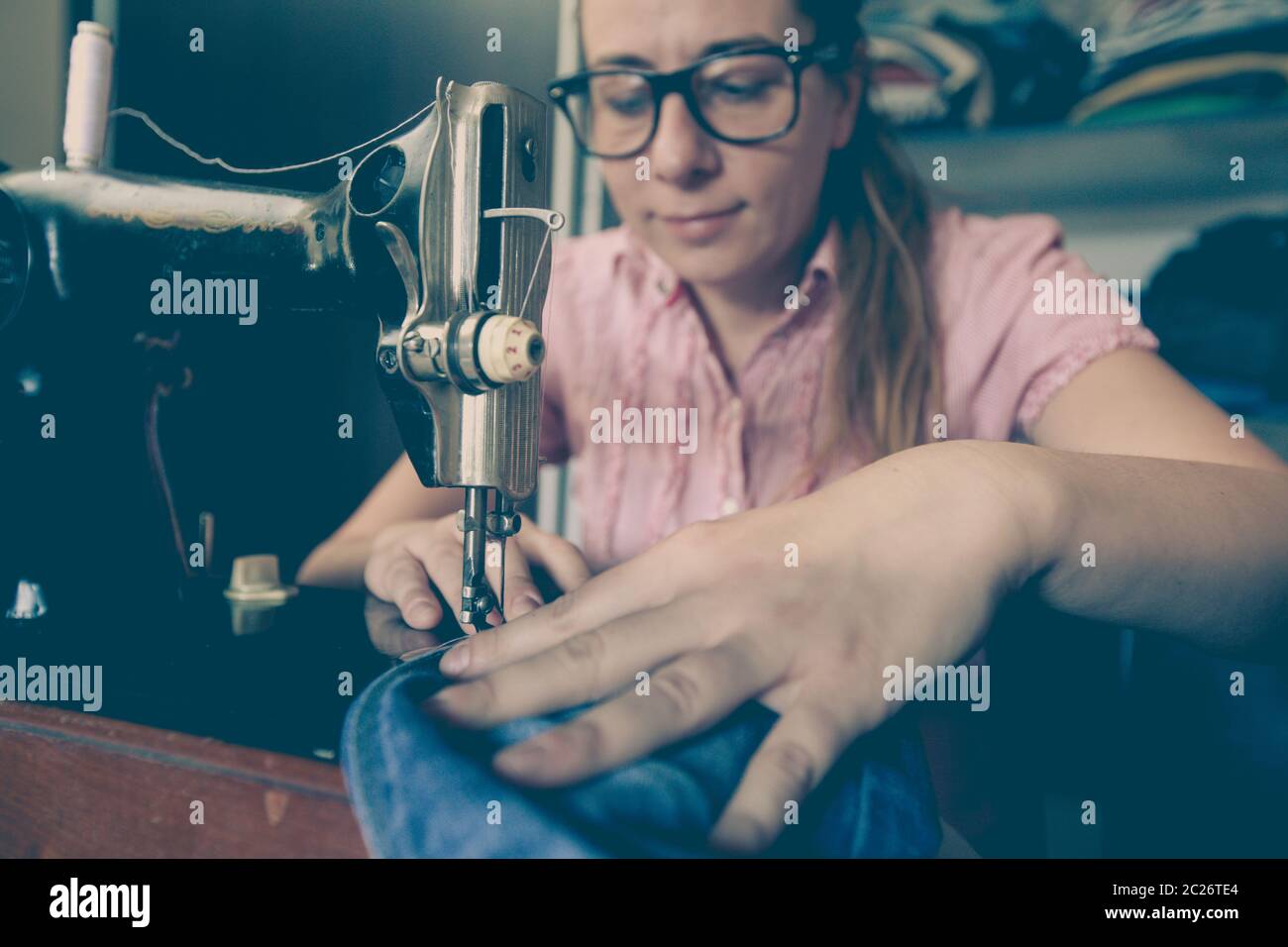 homemaker repairing blue jeans with retro vintage sewing machine at ...