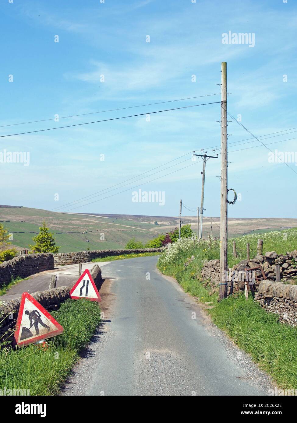 men at work and lane narrowing signs on a narrow country lane with ...