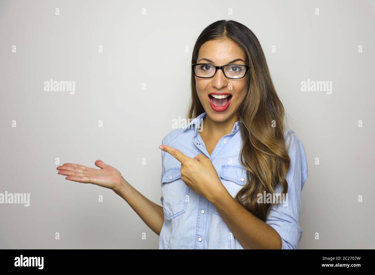 Young woman showing product with open hand palm and pointing finger ...