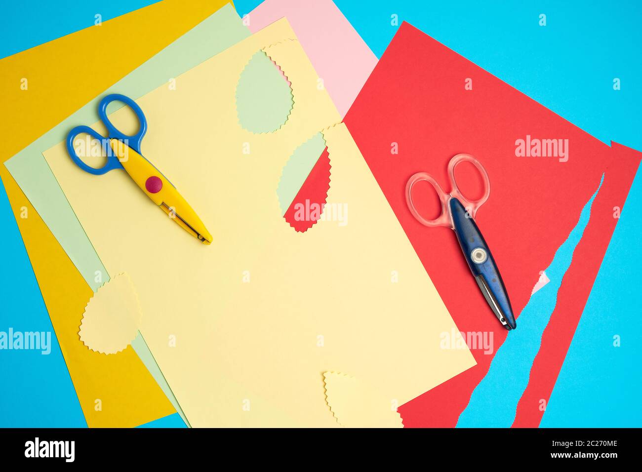 pair of plastic scissors and colored paper for cutting figures ...