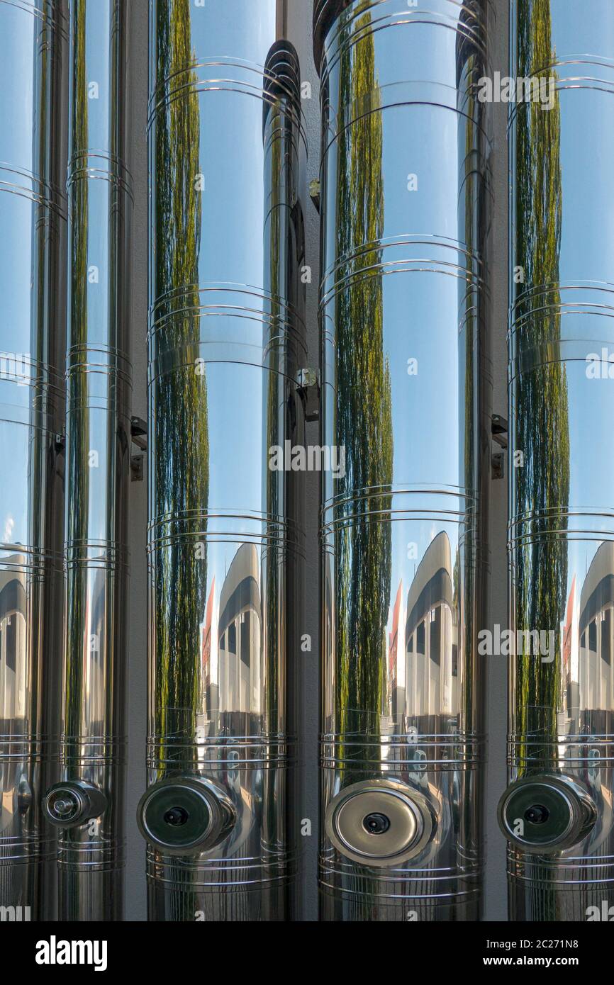Vertical tubes made of stainless steel on a house wall with reflections ...
