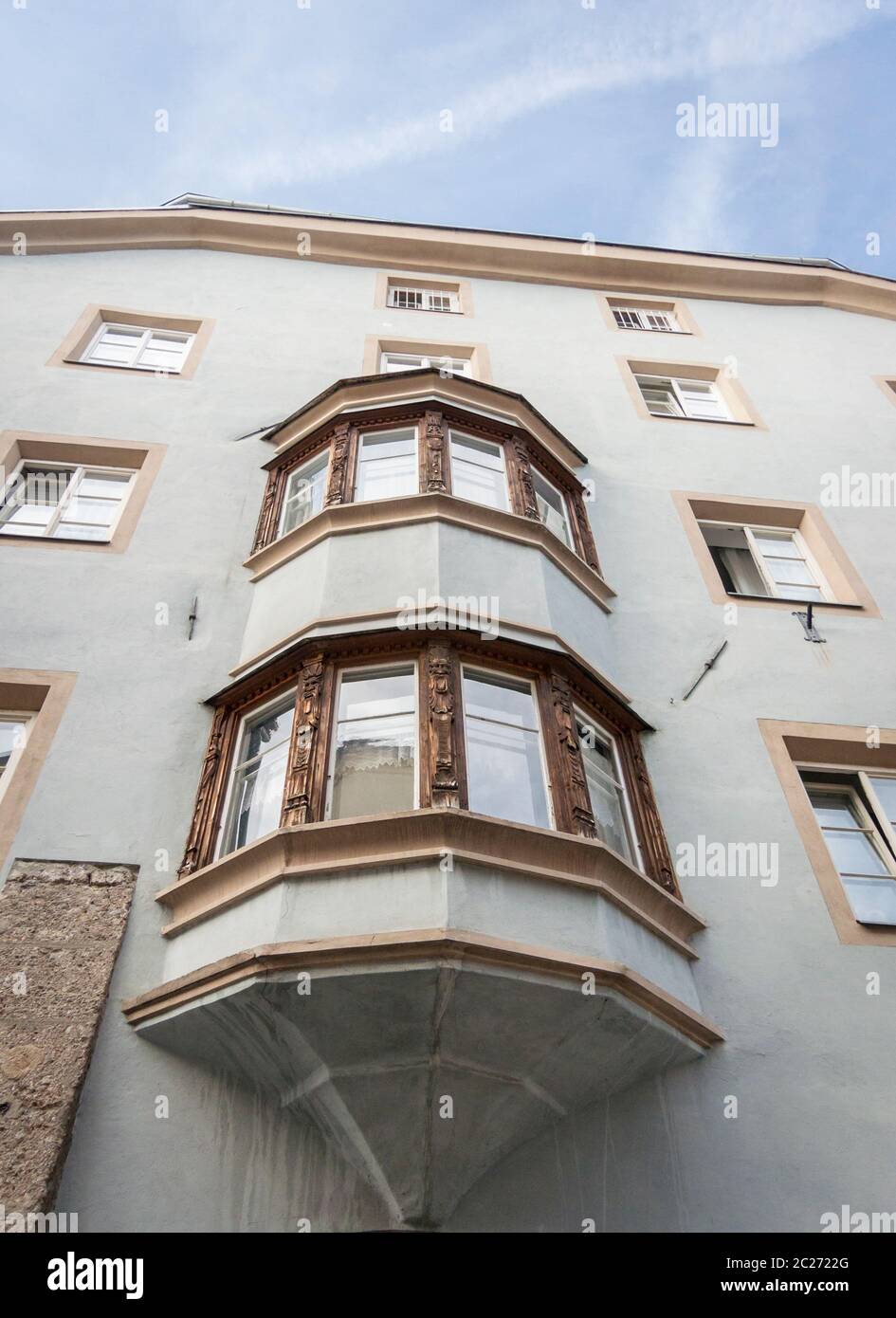 View looking up from below at an ornately carved bay window in an ...