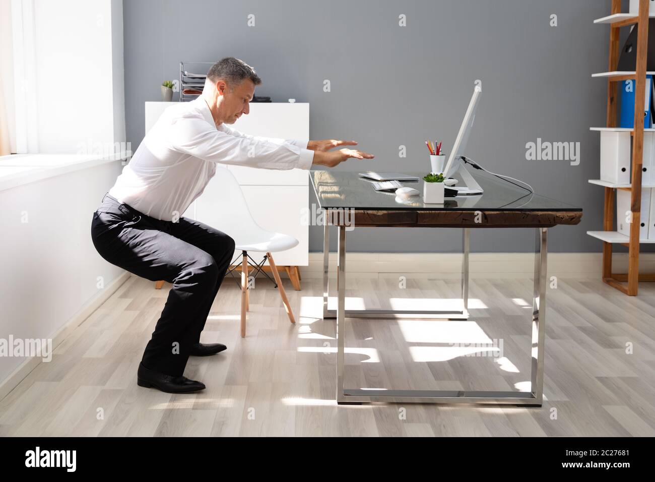 Happy Businessman Doing Squats Exercise In Front Of Computer At Office ...