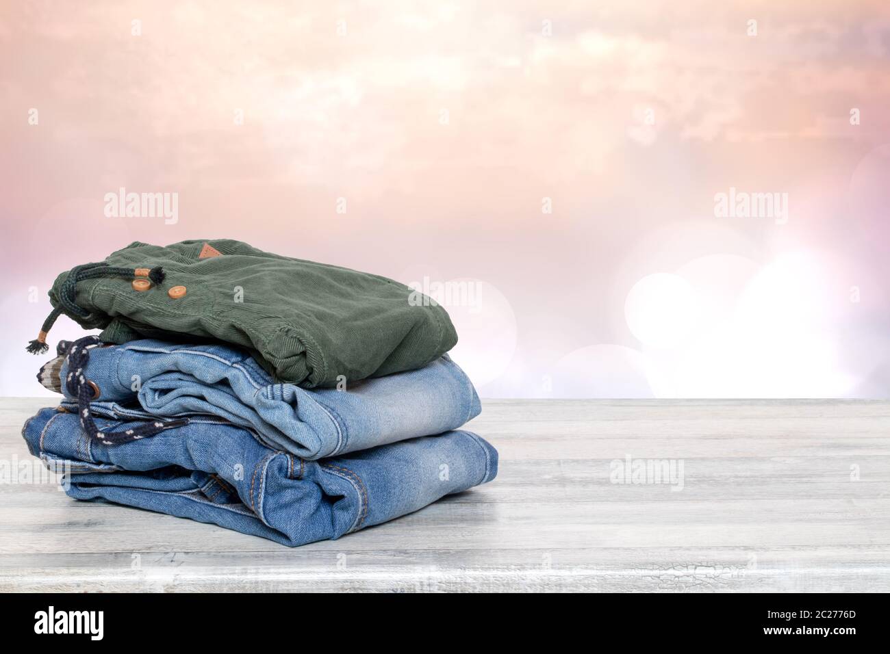 Stack of jeans. Closeup of a pile of colorful denim pants on a bright ...