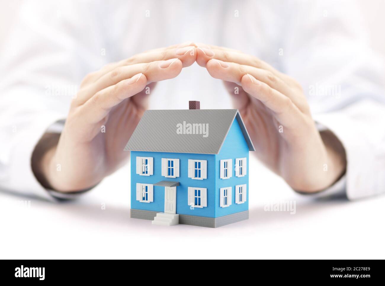 Small blue house covered by hands Stock Photo - Alamy