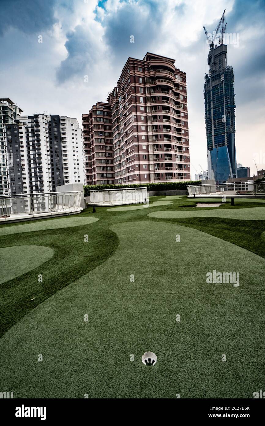 Golf course on the roof of scyscraper over modern buldings and sky ...