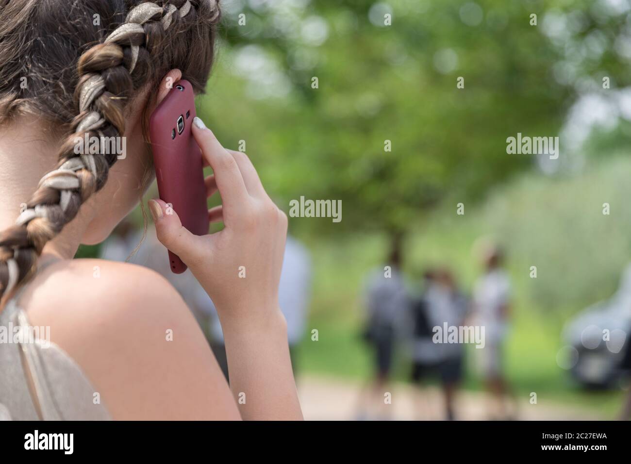 Close-up over the shoulder young girl talking on the mobile phone with ...