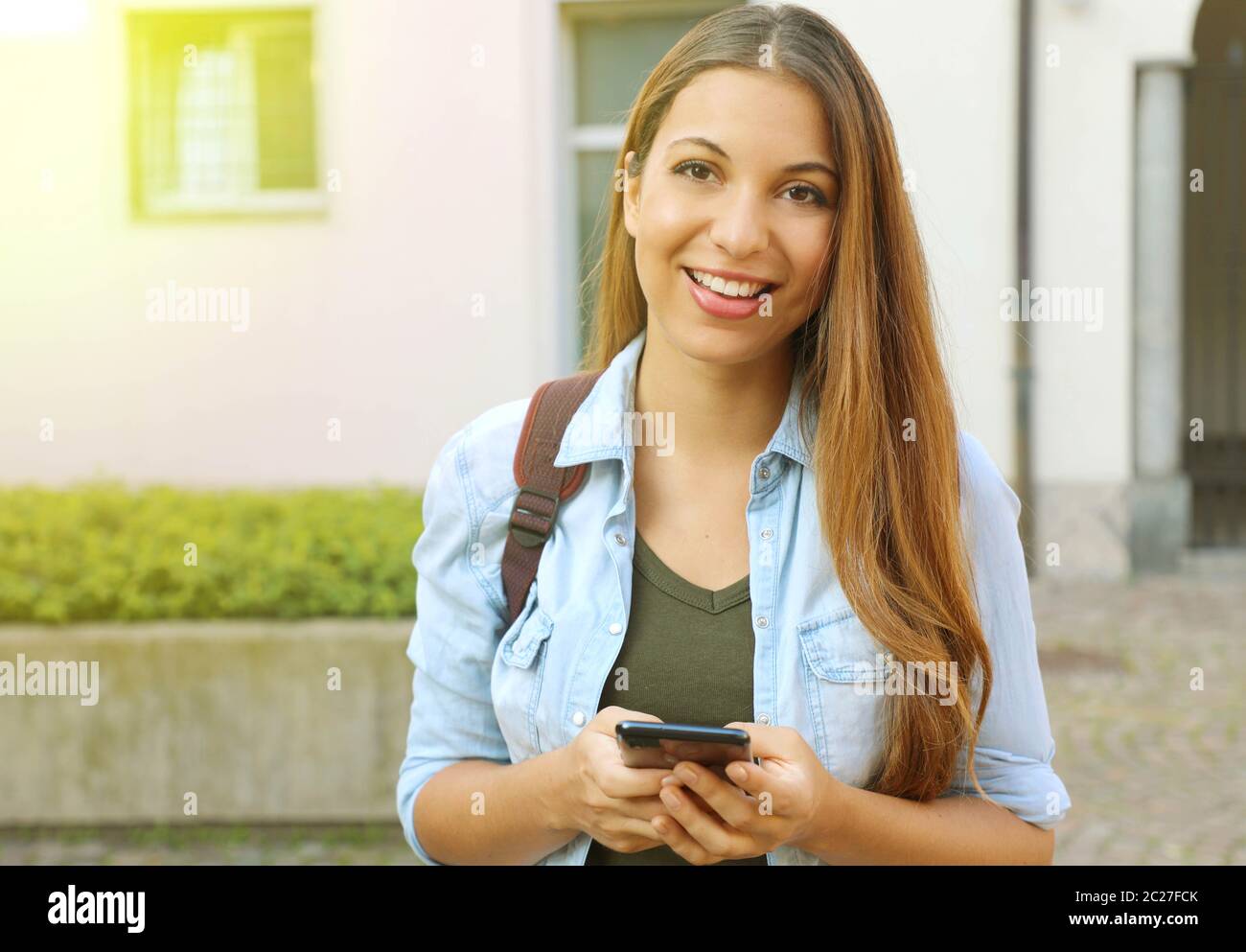 Attractive student girl typing on smart phone and looks at camera Stock ...
