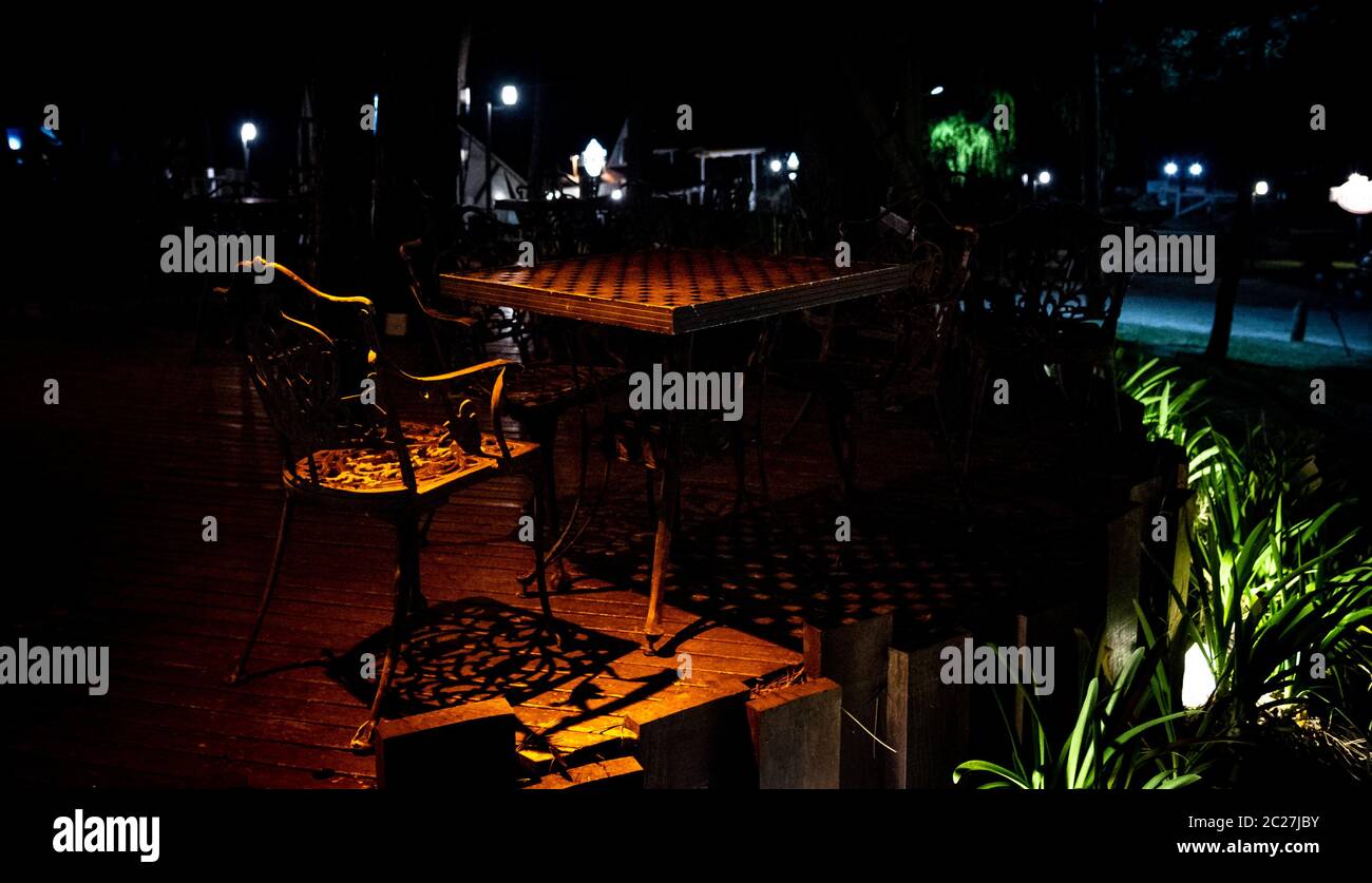 Night scene of an isolated chair and table on a wooden deck of an ...