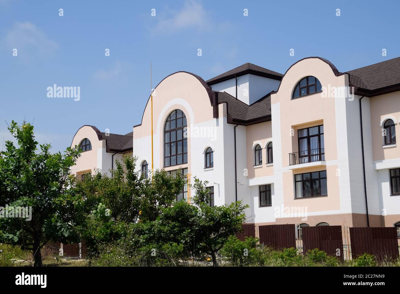 Three-story hotel mansion with a brown metal fence Stock Photo - Alamy