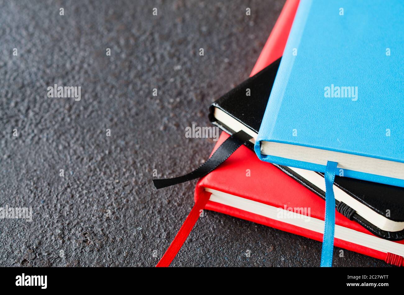 Stack of colorful notebooks for writing or books on dark background ...