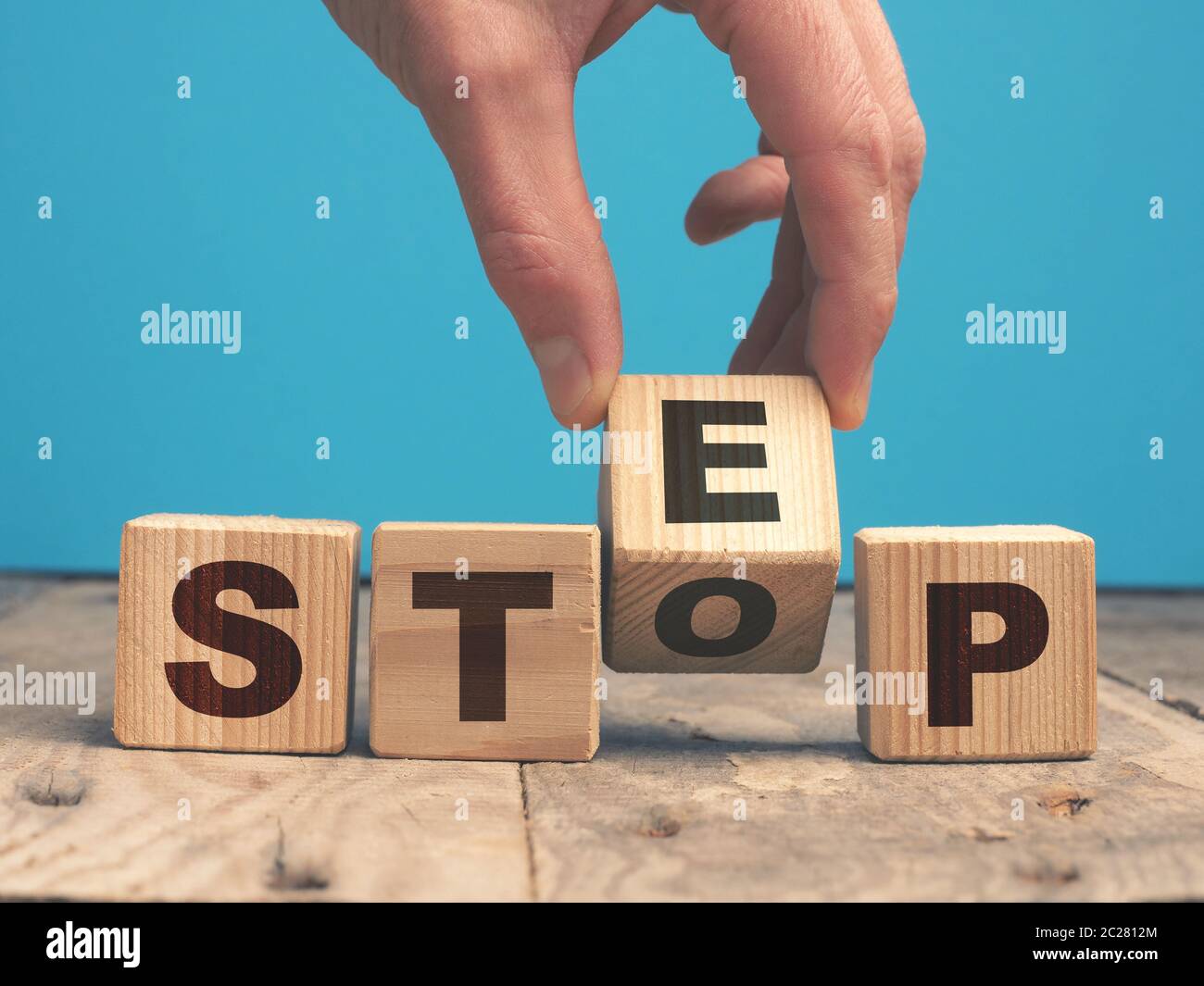 Businessman turns wooden cube with the inscription Step, Motivation or ...