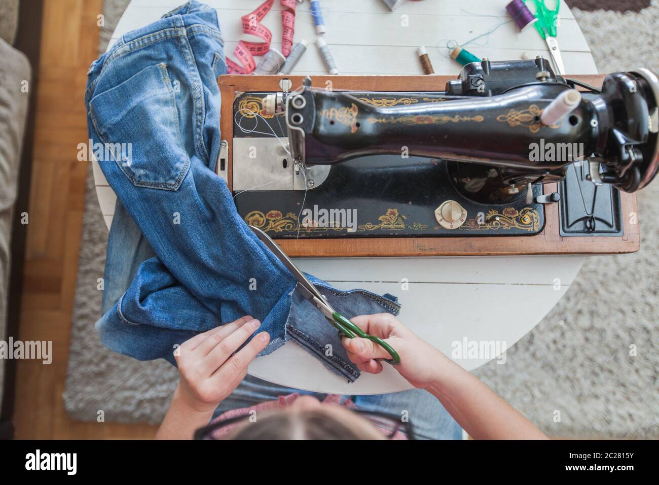 Top view of female tailor using scissors for cutting blue jeans and ...
