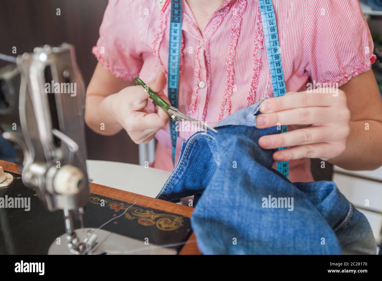 Female hands using scissors for cutting blue jeans and retro sewing ...