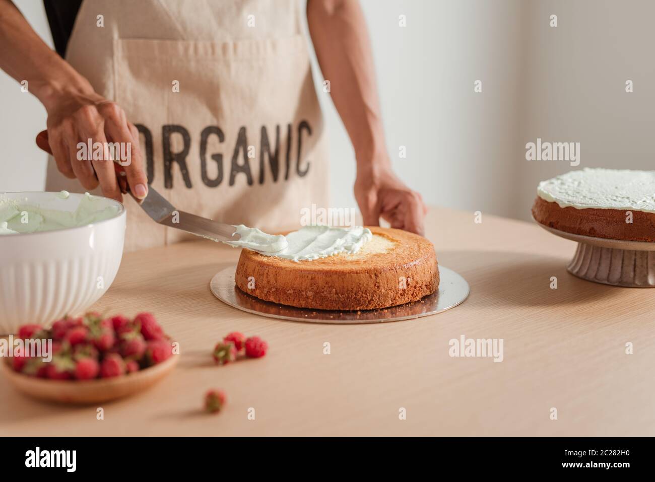 Man pastry chef put icing cream on sponge cake. Making sponge cake ...