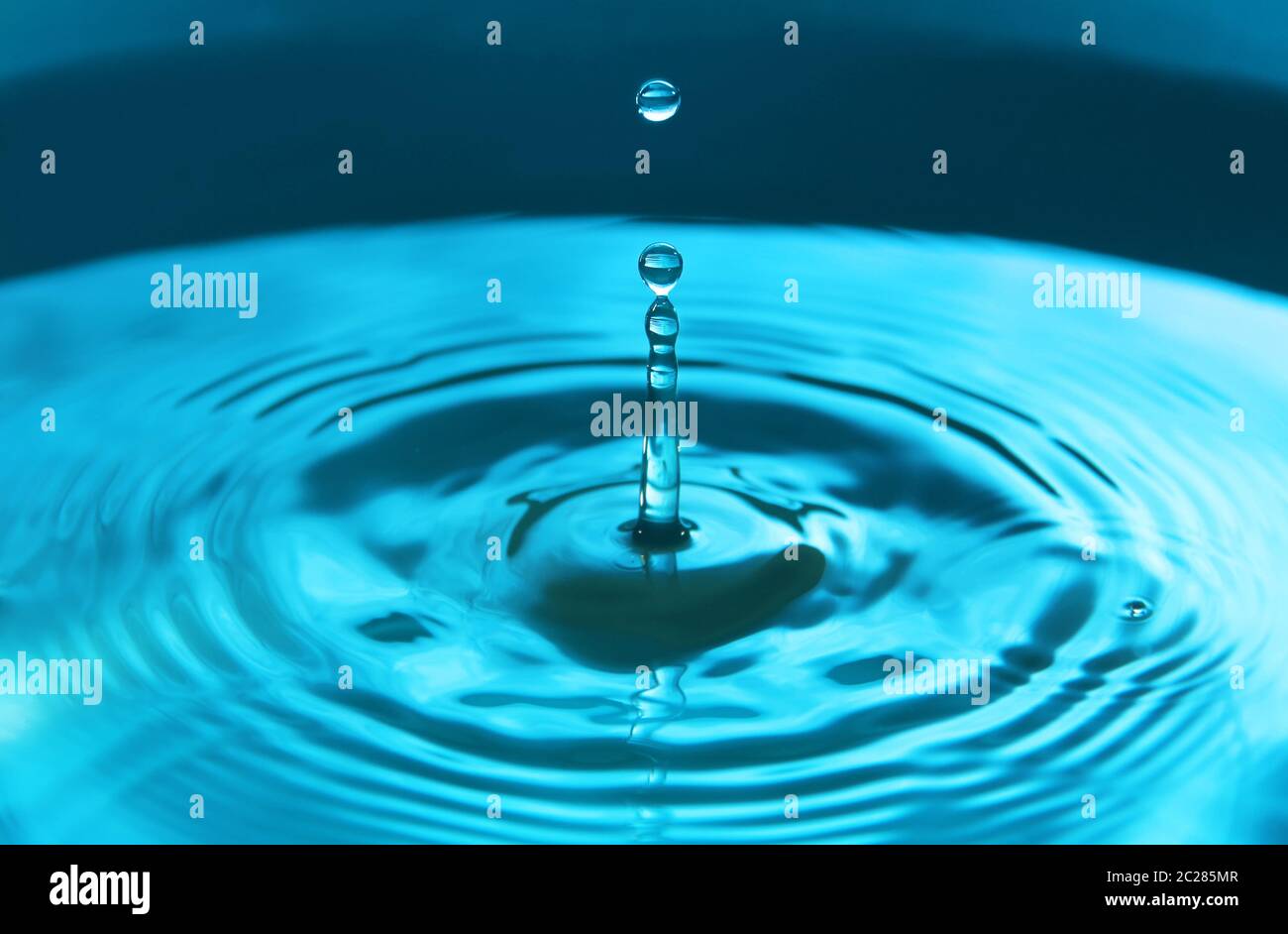 Water drop falling into water making a perfect concentric circles ...