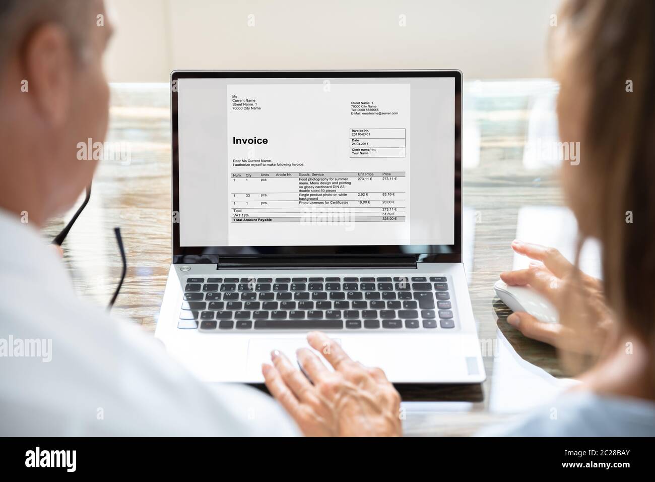 Rear View Of Two Businesspeople Analyzing Invoice On Laptop Stock Photo ...
