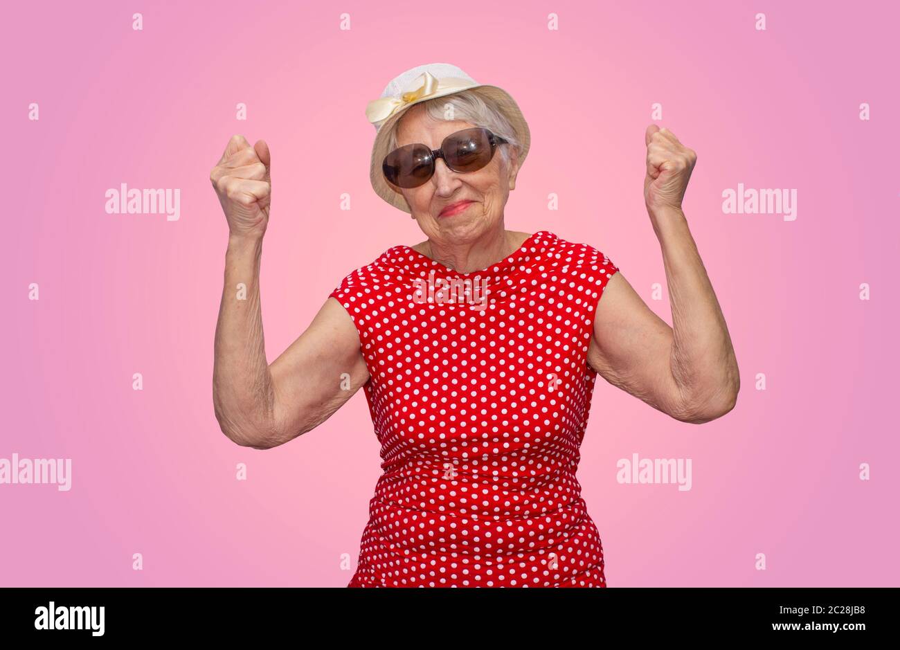 Old smiling woman with happy expression on her face on red studio ...