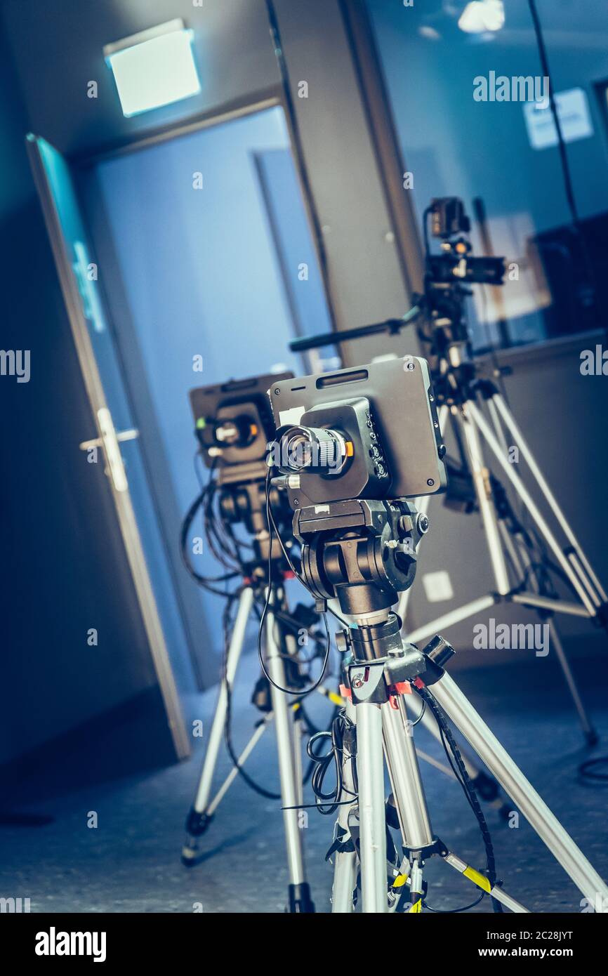 Modern film camera on a tripod in a broadcasting studio, spotlights and ...